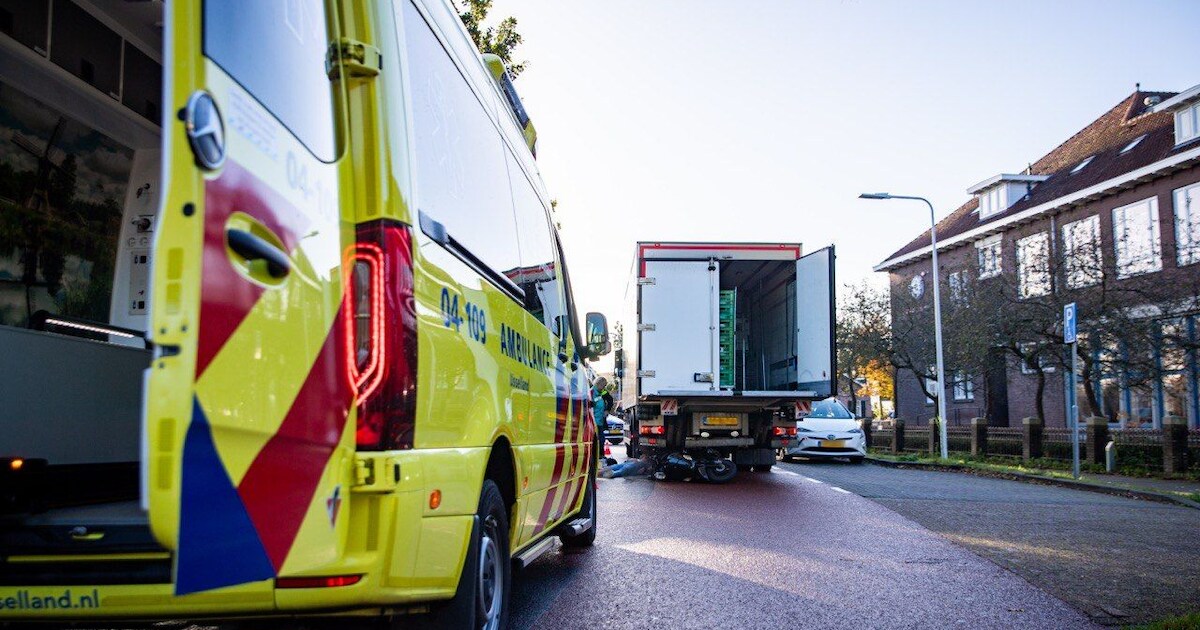 Brommerbestuurder glijdt onder vrachtwagen na aanrijding met auto in ...